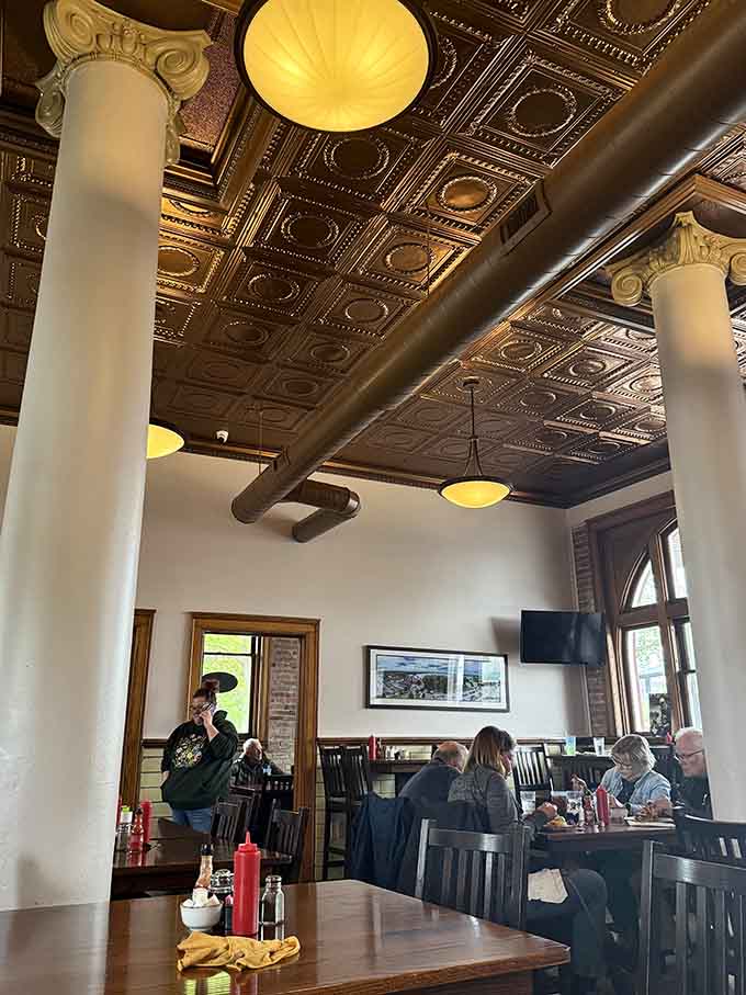 Soaring ceilings with decorative tiles and tall white columns create a dining space that feels both grand and welcoming, like eating in a beautiful historic monument.