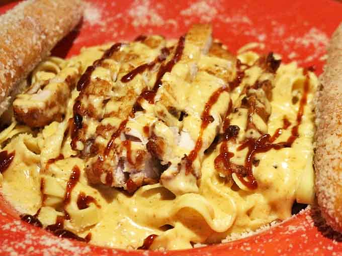 Comfort food reaches new heights with this creamy fettuccine pasta topped with crispy chicken and drizzled with BBQ sauce, flanked by sugared breadsticks.