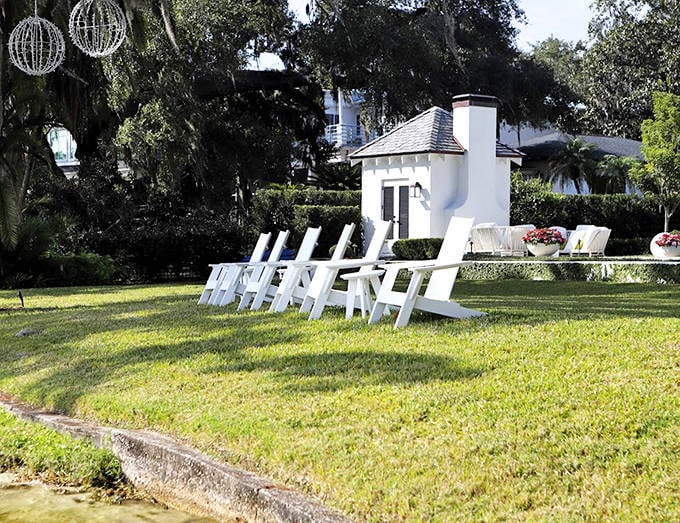 Adirondack chairs invite relaxation on manicured lawns that slope gently toward the water, showcasing Winter Park's blend of natural beauty and refined living.