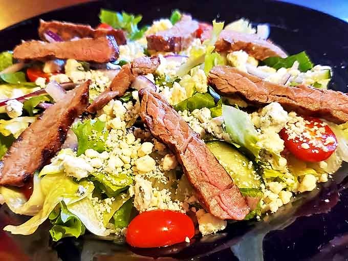 The steak salad balances indulgence and freshness with tender strips of beef atop crisp greens and crumbled blue cheese.