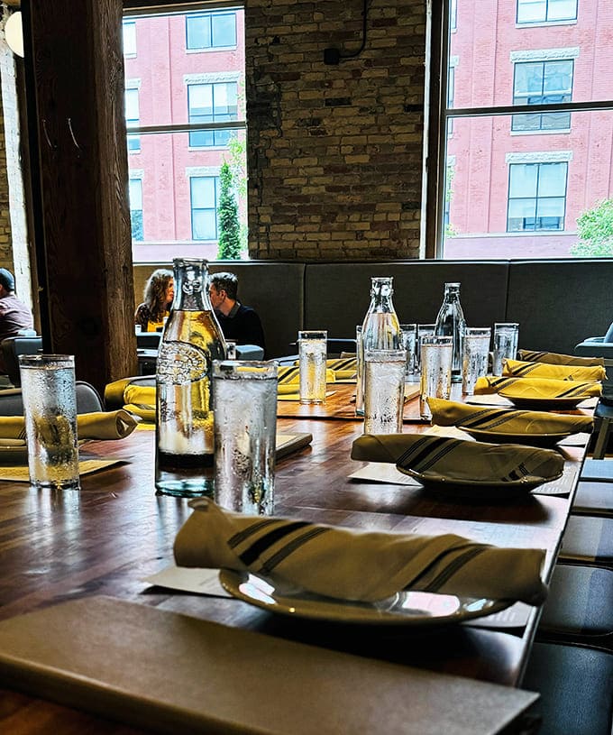 Tables set with understated elegance, awaiting the evening's stories and laughter. Water glasses catching light like diamonds on wood.
