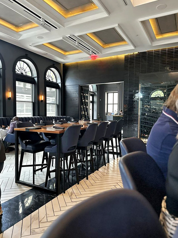 Elegant dining stations await beneath illuminated coffers, where herringbone floors lead to culinary adventures in this historic space.