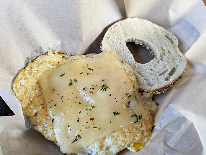 Simple pleasures done right: a perfectly fried egg melts into cheese on a fresh bagel, proving sometimes less truly is more.