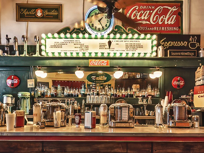 The soda fountain counter, where magic happens daily as skilled hands craft drinks that have delighted Phoenicians for generations.