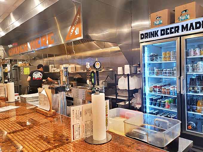 "ORDER HERE" glows in orange against stainless steel, while coolers stocked with craft brews promise refreshment for heat-seeking wing enthusiasts.
