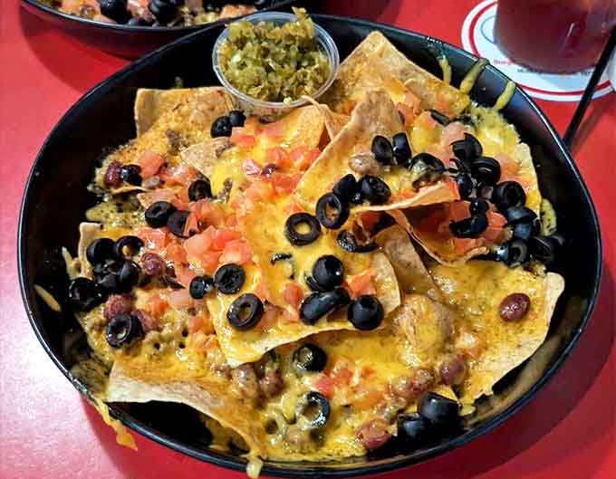 Buffalo Chicken Nacho Supreme lives up to its name with layers of chips, cheese, chicken, and toppings that transform snacking into a legitimate meal requiring both hands and commitment.