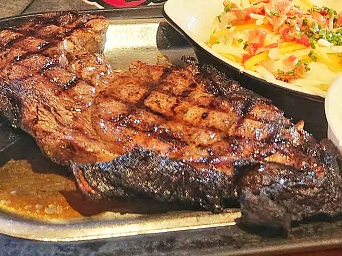 A perfectly grilled steak sizzles on its plate, showcasing the kitchen's mastery of simple pleasures executed with exceptional skill and attention to detail.