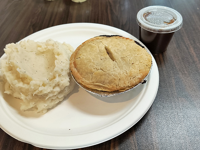 Mashed potatoes accompany a golden chicken pot pie, its steam escaping through the signature slash &ndash; comfort food that transcends international borders.