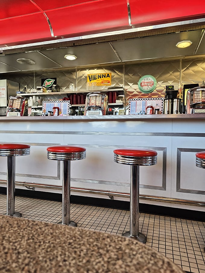 Chrome-trimmed counter seating invites solo diners to enjoy front-row views of short-order cooking magic while perched on fire-engine red stools.