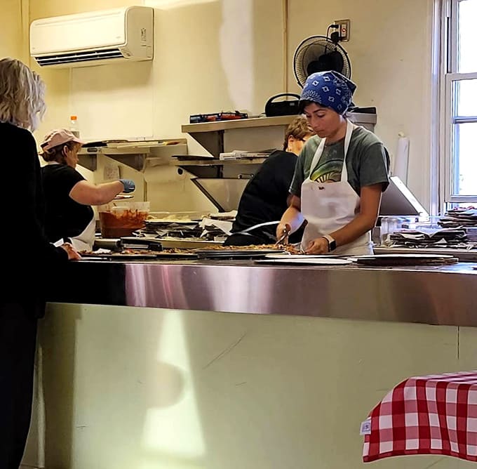 Kitchen staff working with the focused efficiency of people who've perfected their craft, turning out pizza after perfect pizza.