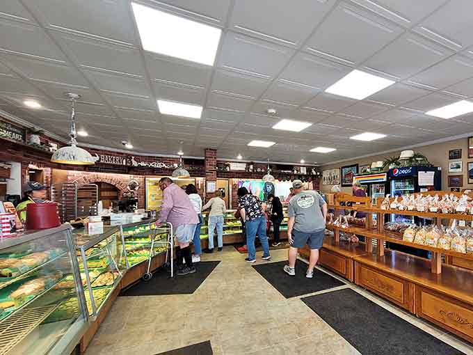 The interior reveals a bustling bakery where customers line up for their fix, and those display cases promise something delicious for every craving and occasion.