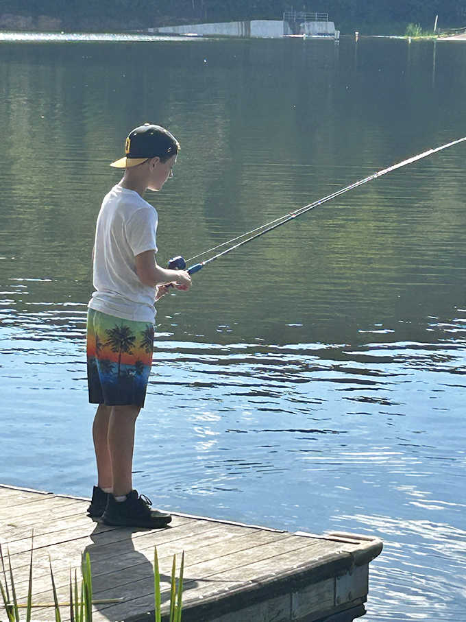Patience personified &ndash; a young angler demonstrates the timeless art of waiting for the perfect catch as sunlight dances across the water.
