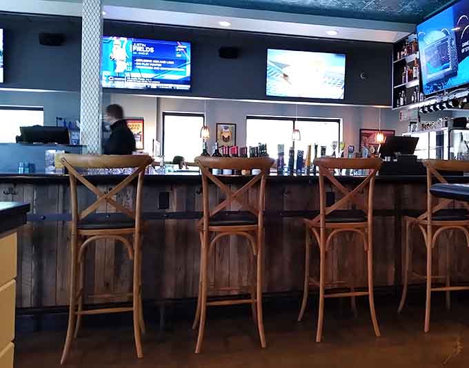 The bar area features multiple screens and a well-stocked selection, perfect for catching the game while enjoying a craft beer or creative cocktail.