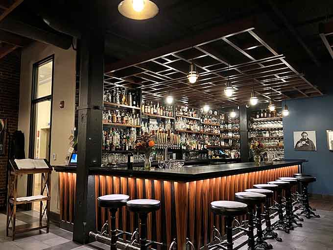 The bar at Nosh showcases an impressive spirits selection that would make any cocktail enthusiast happy, with bottles stretching toward the ceiling like liquid possibilities.