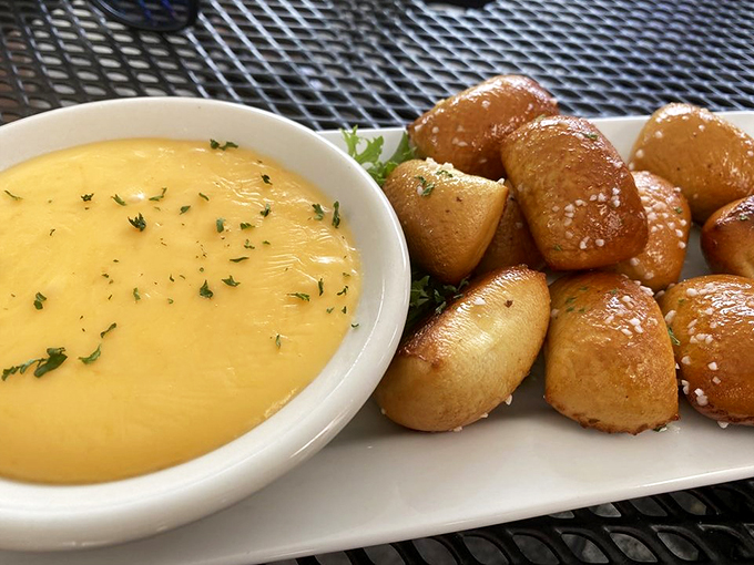 Golden pretzel bites beside velvety cheese sauce &ndash; a match made in appetizer heaven that's impossible to resist.