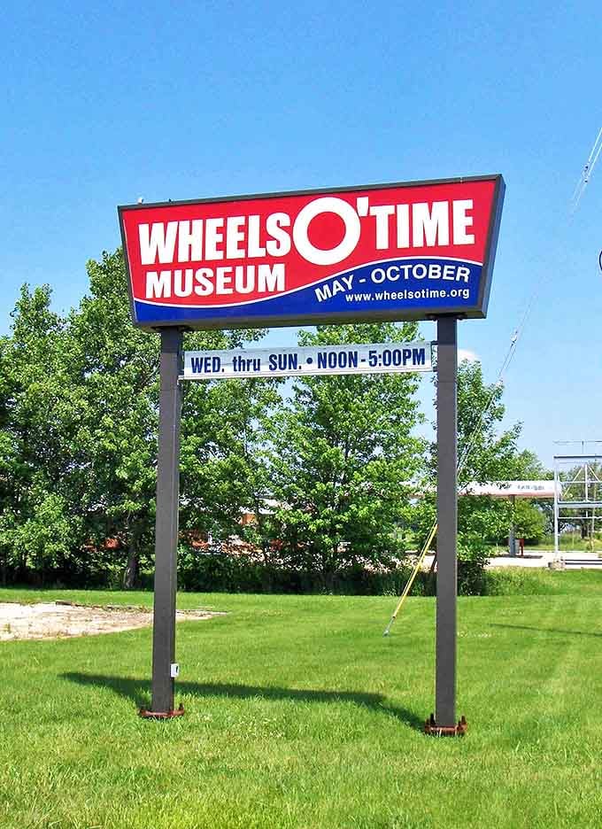 The bold red and blue signage announces operating hours with vintage flair, promising mechanical delights from May through October.