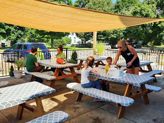 The outdoor patio offers a sun-dappled retreat where picnic tables invite lingering conversations over exceptional food.