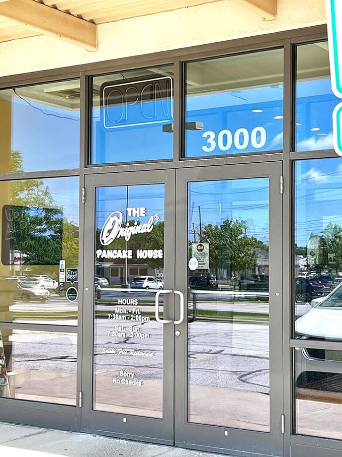 The entrance welcomes you with posted hours and promises of pancake perfection waiting just beyond those doors.