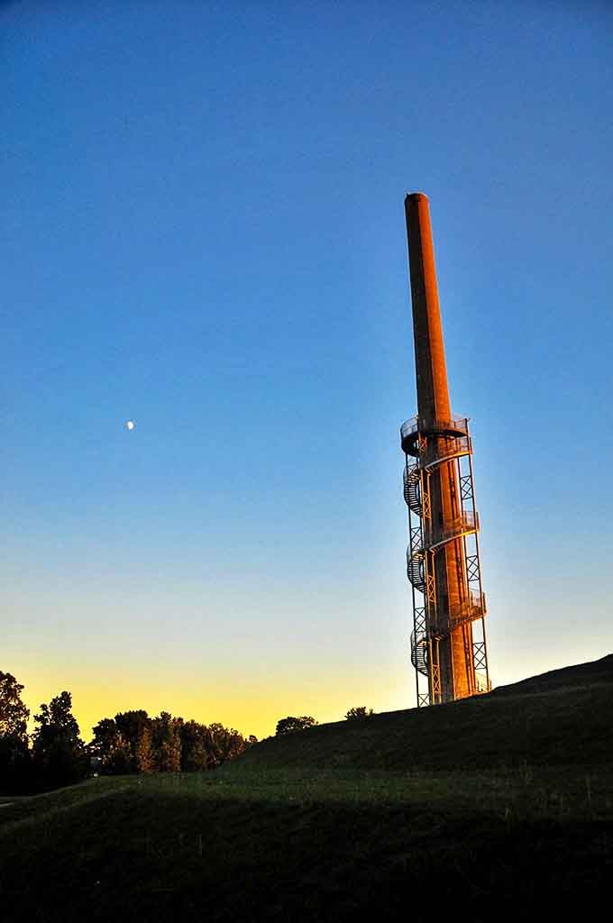 As day surrenders to dusk, the tower stands sentinel against the twilight sky, its industrial silhouette softened by the golden hour glow.