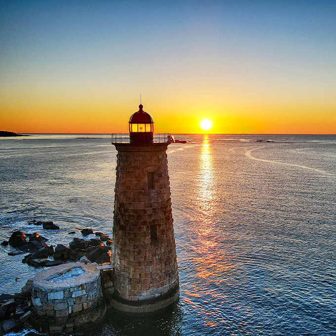 Whaleback Lighthouse stands against a blazing sunset, creating the kind of postcard-perfect scene that makes amateur photographers feel like professionals.