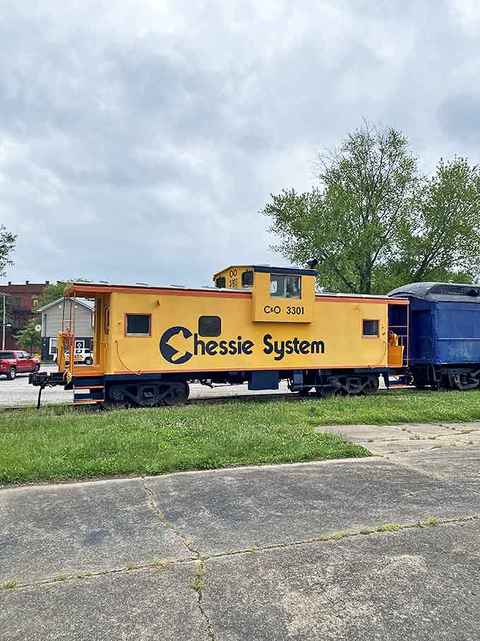 The cheerful yellow Chessie System caboose stands guard at Harmar Village, a sunny sentinel of America's railroad golden age.