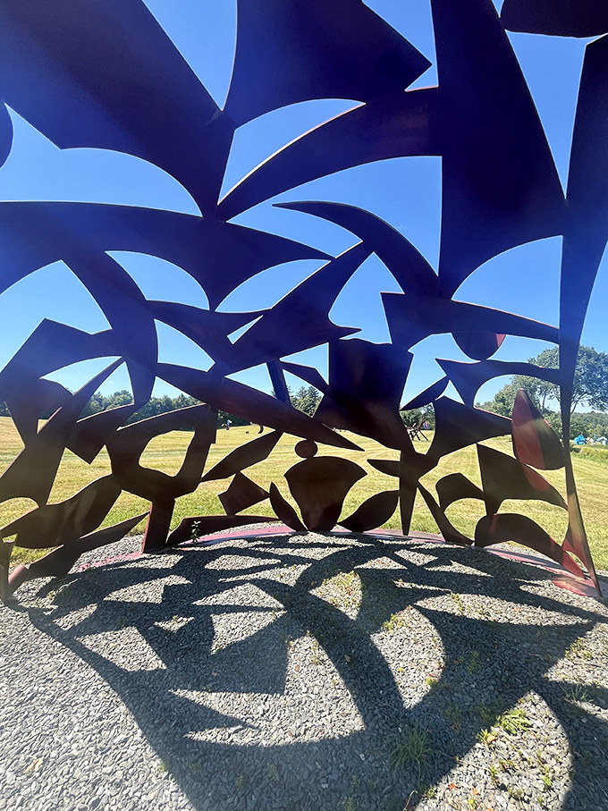 Abstract forms create unexpected shadows across the gravel base, doubling the visual impact as the sun shifts position.