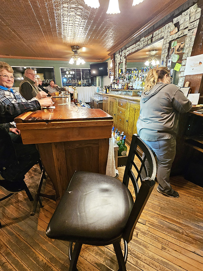 The bar area, where dollar bills tell stories and old fashioneds are crafted with the precision of cocktail artisans who've perfected their craft.