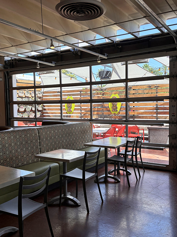 Comfortable booth seating with garage-style windows creates an indoor-outdoor feel, letting in desert light while maintaining the island vibe.