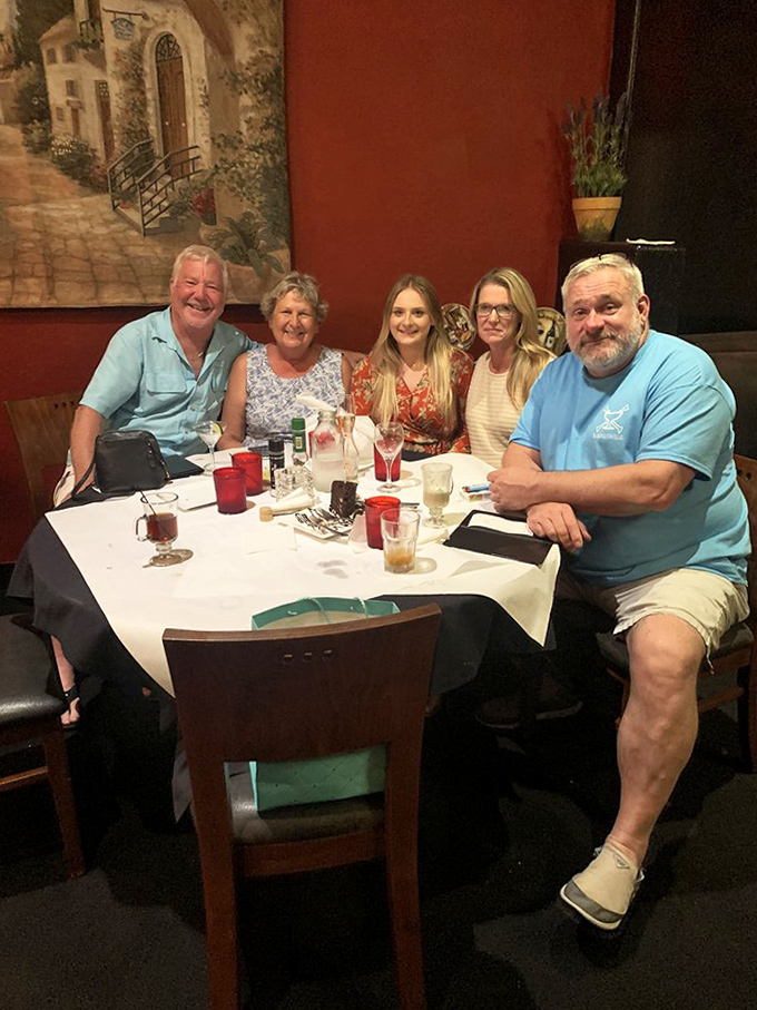 Happy diners gathered around a white-clothed table &ndash; the universal expression of satisfaction that comes from sharing good food with good company.