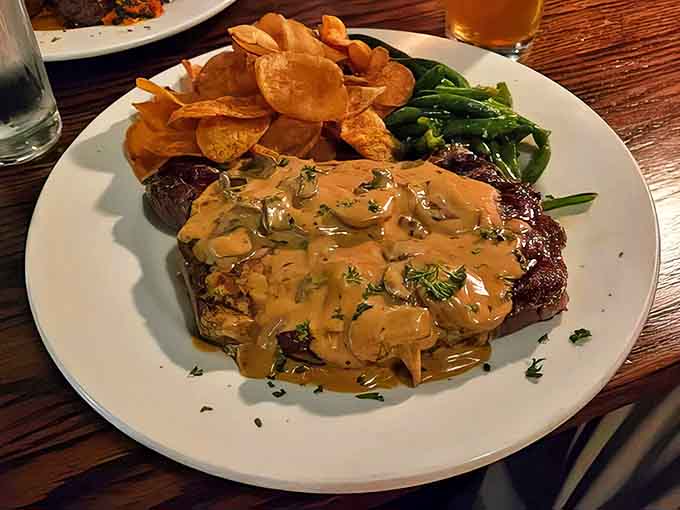 The steak arrives bathed in mushroom sauce so good you'll want to bottle it, accompanied by house-made potato chips and vibrant green beans.