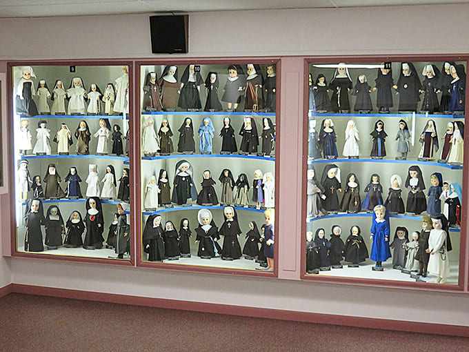 Row upon row of meticulously dressed nun dolls stand in illuminated display cases, showcasing the variety of religious habits throughout history.