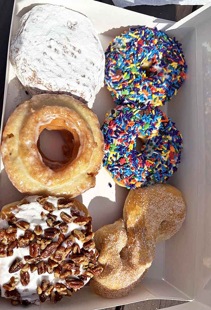 Assorted Half-Dozen: A box of joy featuring sprinkles, glazes, and toppings that make decision-making deliciously difficult.