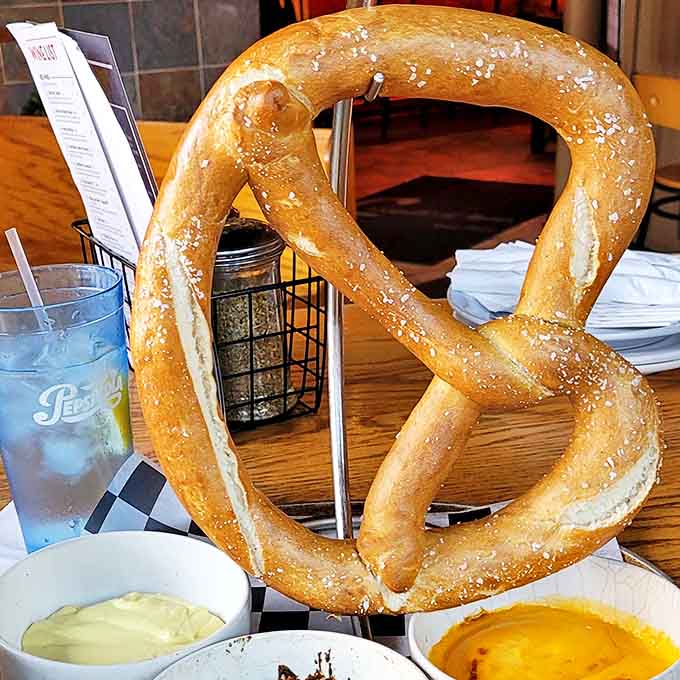 The pretzel arrives like royalty on its custom stand &ndash; golden, glistening, and large enough to create an immediate "wow" moment at the table.