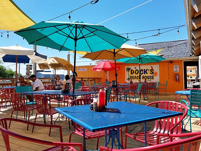 Colorful outdoor tables under umbrellas create a Caribbean courtyard vibe that makes every meal feel like a mini-vacation.