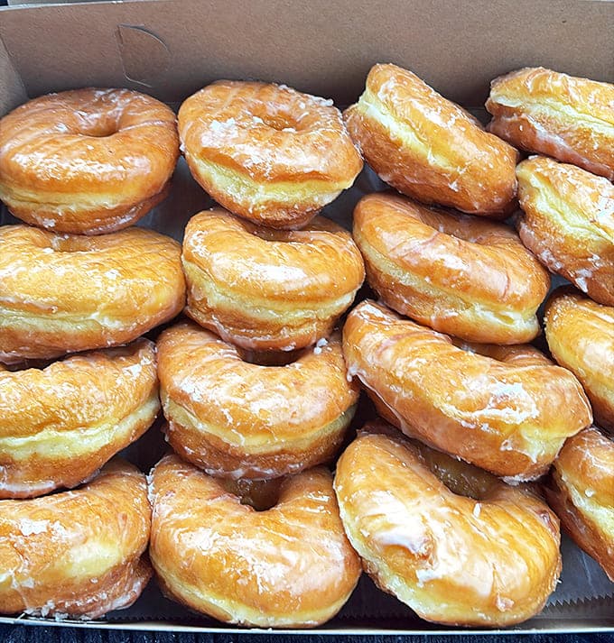 Glazed Donuts: The Platonic ideal of donut perfection &ndash; golden, gleaming, and stacked with the precision of delicious dominoes waiting to fall.