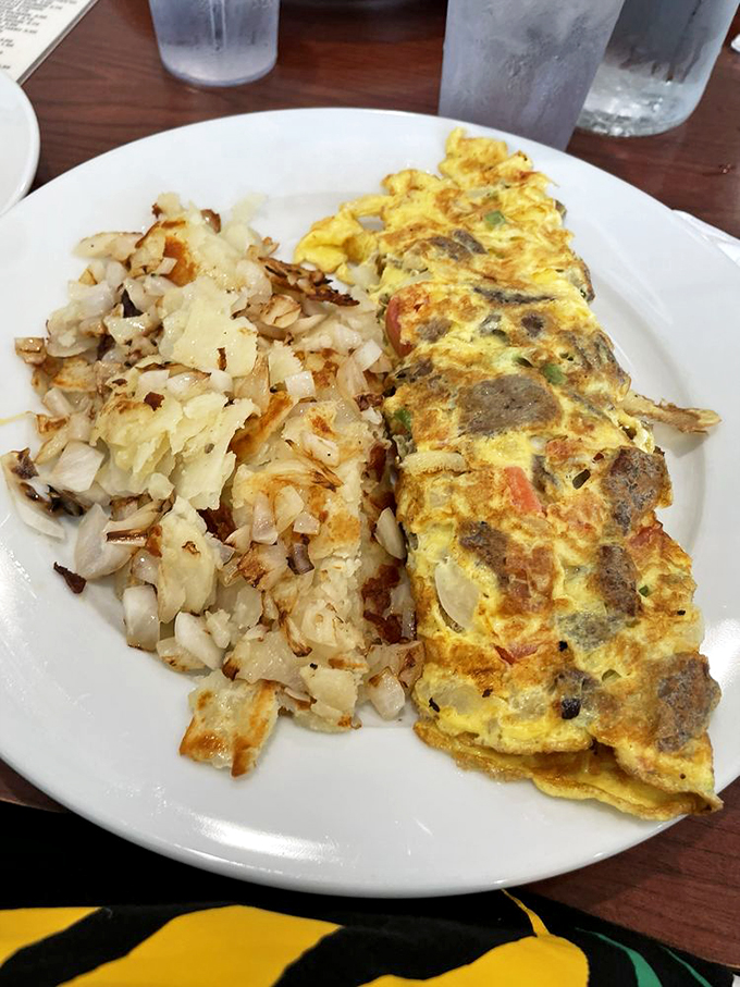 A perfectly executed omelet shares the plate with hash browns that achieved the ideal crispy-to-tender ratio.