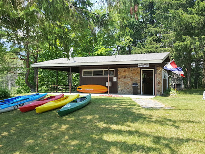 Colorful kayaks stand ready for adventure, like a rainbow grounded beside the park's charming stone building.