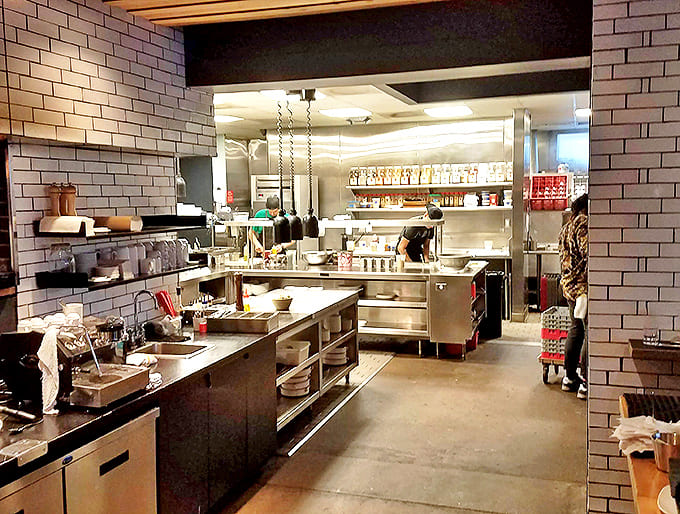 Kitchen: The heart of the operation exposed for all to see. Gleaming stainless steel and white tile create a canvas where culinary magic unfolds.