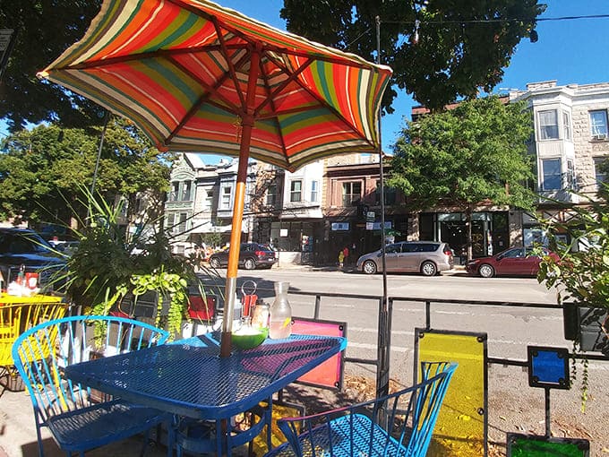 Rainbow chairs under striped umbrellas make outdoor dining feel like a party, even on a Tuesday morning.