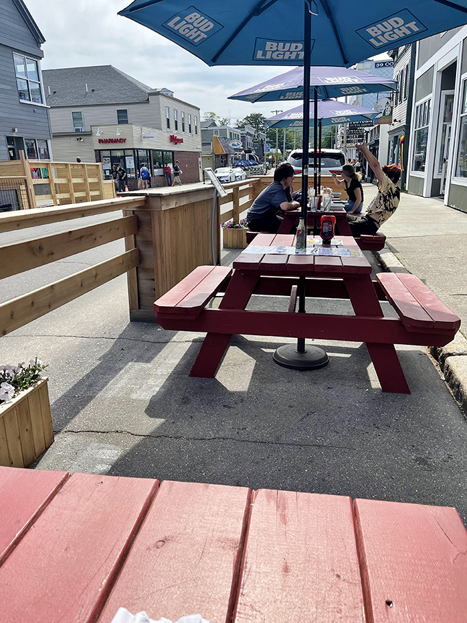 Red picnic tables offer al fresco dining along Cottage Street, perfect for people-watching during Bar Harbor's bustling summer season.
