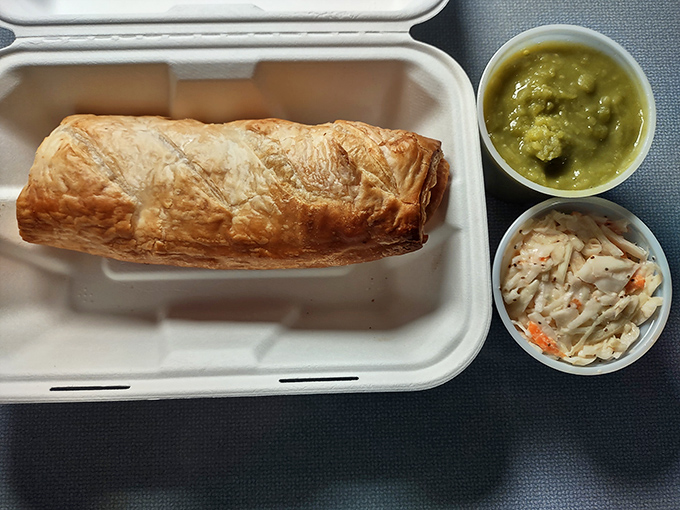 A perfectly executed sausage roll with sides of coleslaw and mushy peas &ndash; portable British perfection wrapped in flaky, buttery pastry.