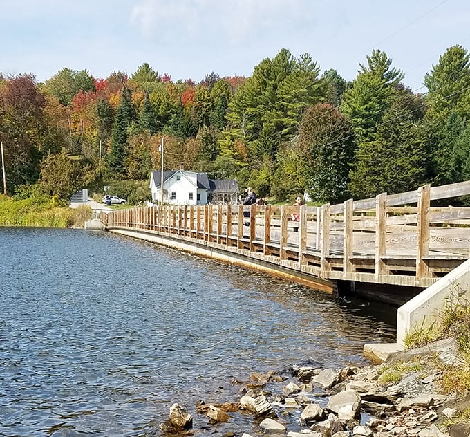 Engineering meets artistry in this side view, where the bridge's wooden railings create rhythm against the lake's fluid canvas.