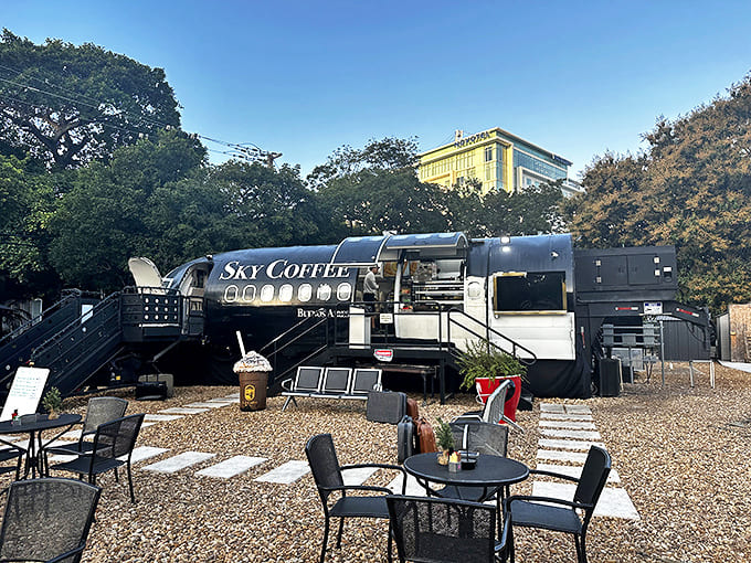 Gravel pathways lead between outdoor tables where patrons can enjoy their beverages while admiring the converted aircraft from different angles.
