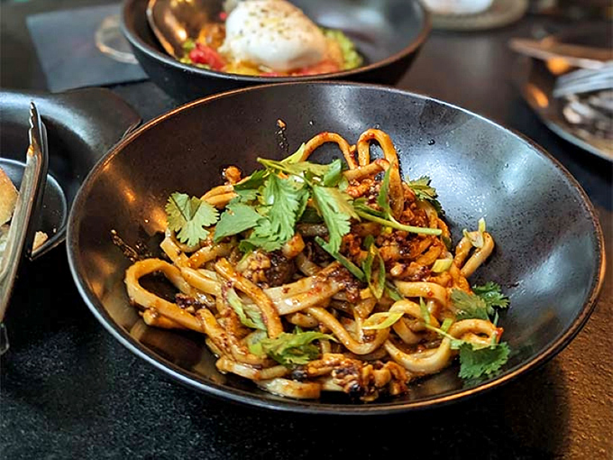 Spicy noodles steam with promise, their tangle of perfectly cooked strands, vegetables, and aromatics delivering heat that builds rather than overwhelms.