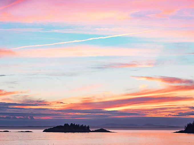 Sunset transforms Stonington's waters into a canvas of pink and gold, silhouetting the scattered islands of Merchant Row.