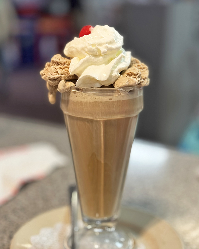 This isn't just a chocolate milkshake &ndash; it's a glass tower of velvety decadence topped with whipped cream and a cherry sentinel.