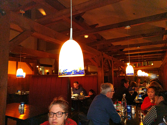 The dining room buzzes with the pleasant energy of satisfied patrons enjoying good food and better company under warm pendant lighting.