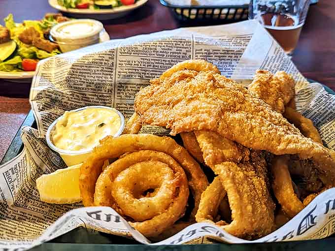 Fish and chips served properly on newspaper with golden onion rings &ndash; a British classic executed with Michigan flair.