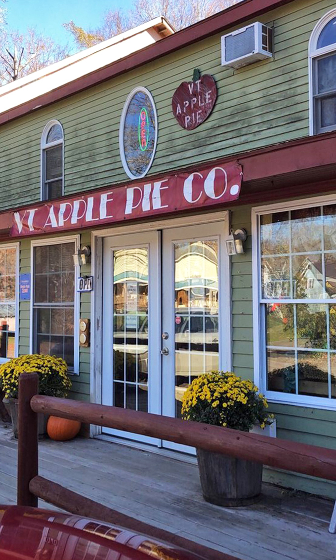 The welcoming entrance, flanked by seasonal mums and rustic wooden railings, promises comfort and satisfaction to all who cross its threshold.
