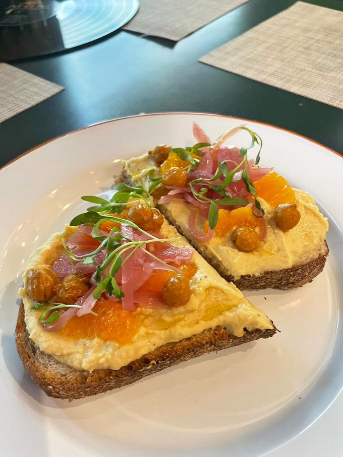 Toast transcendence &ndash; humble bread elevated to art form with hummus, citrus, pickled onions and microgreens creating a symphony of flavor and texture.